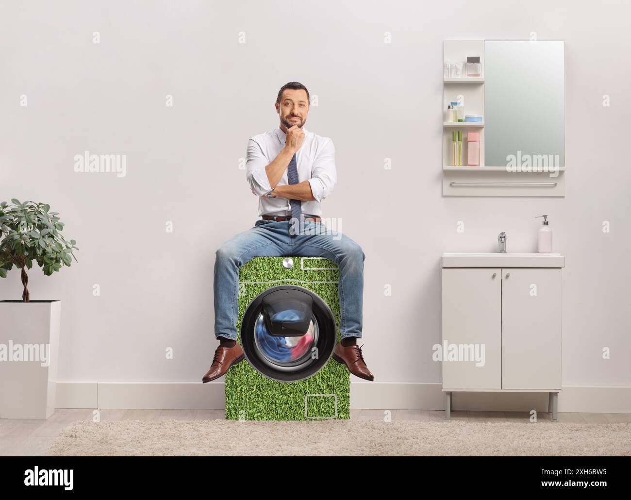 Businessman in a bathroom sitting on top of a washing machine and ...