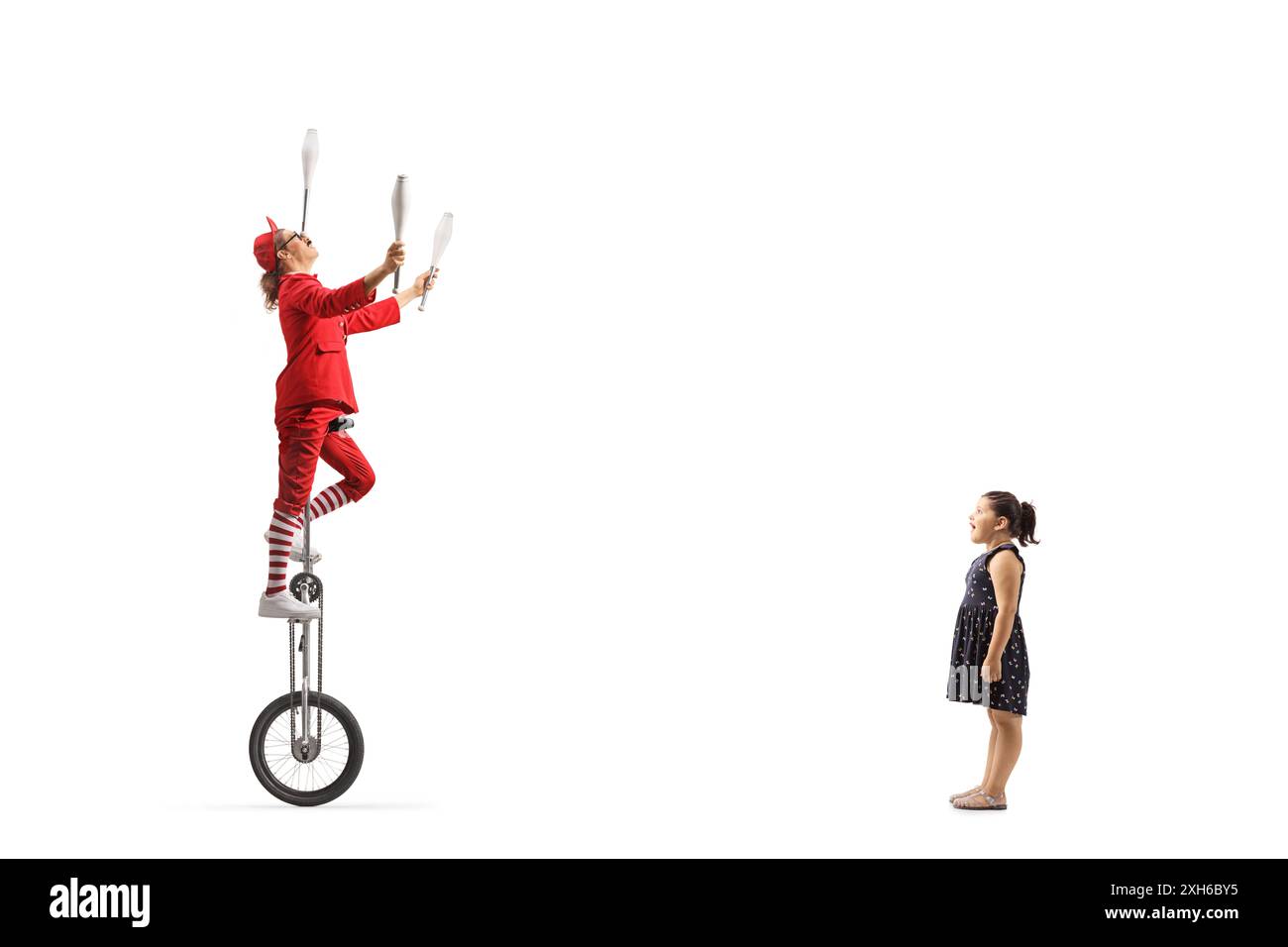 Girl watching an acrobat riding a unicycle and juggling isolated on ...