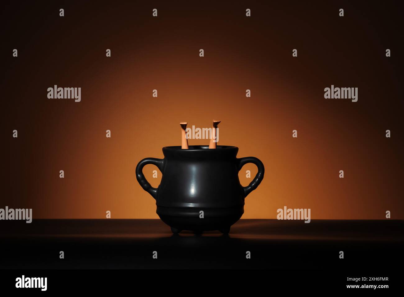 Mysterious black cauldron with witch legs protruding, On pumpkin orange ...