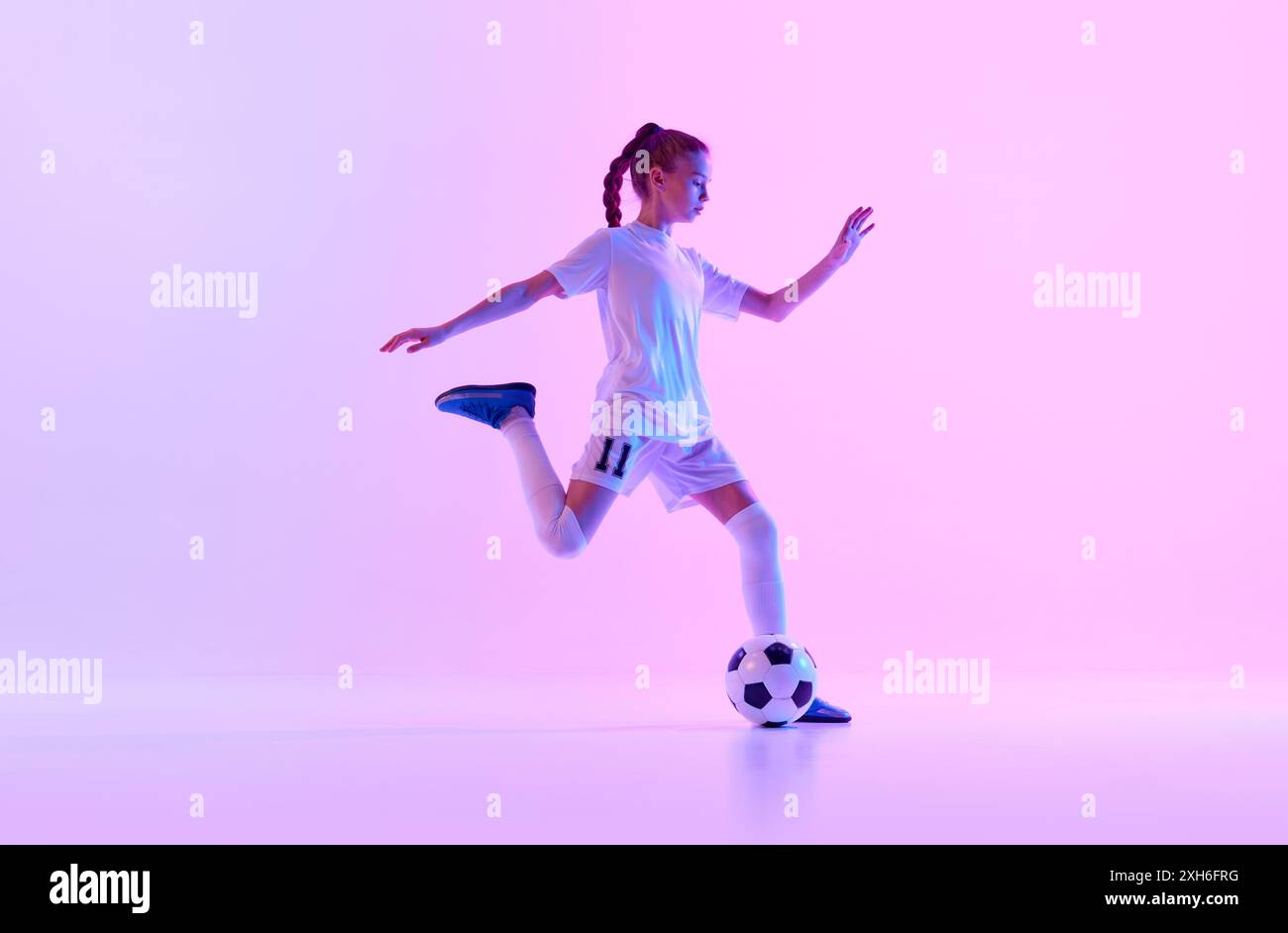 Concentrated female football player. teen girl in motion, kicking ball ...