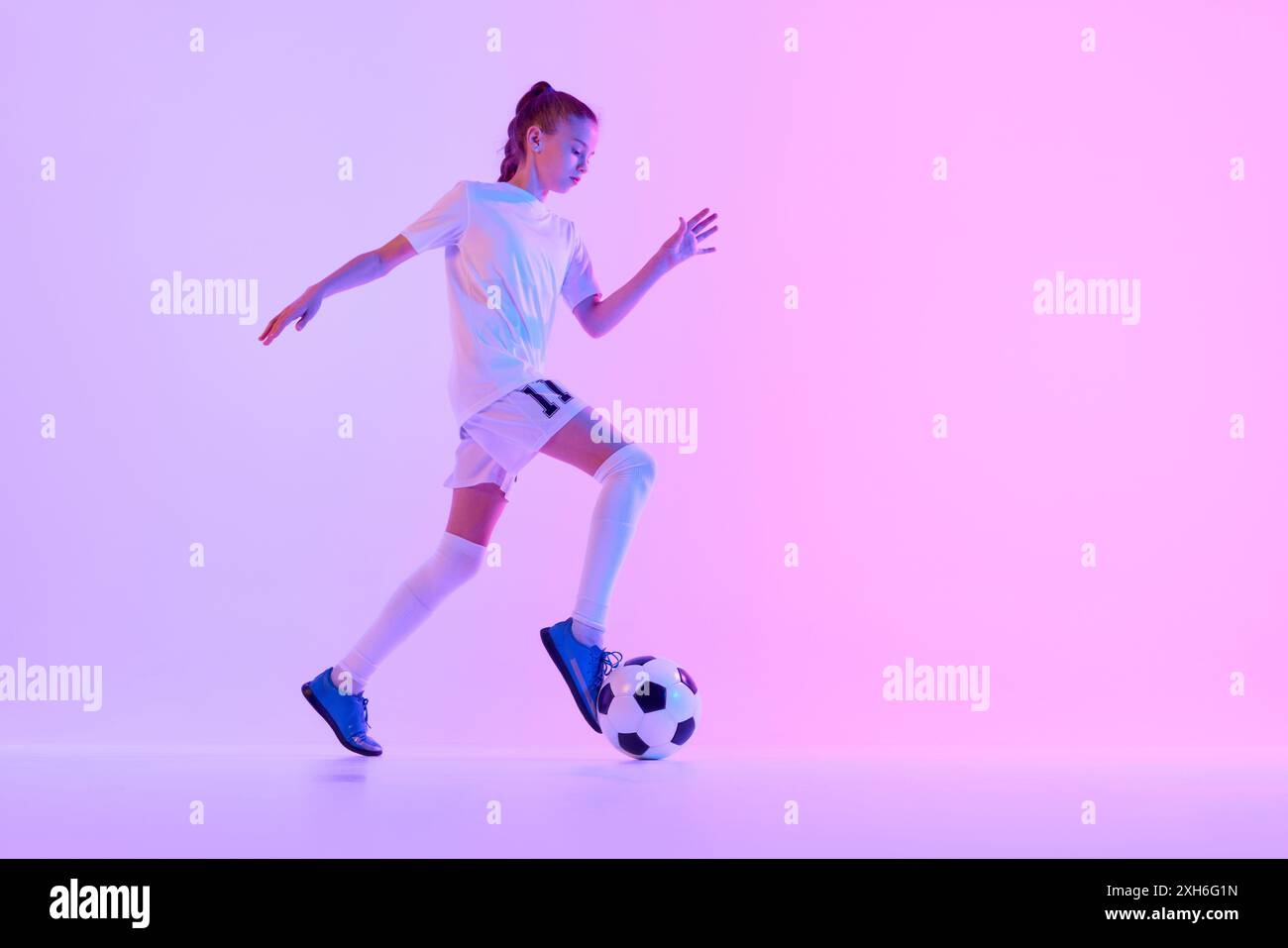 Concentrated teen girl, soccer player training, dribbling ball against ...