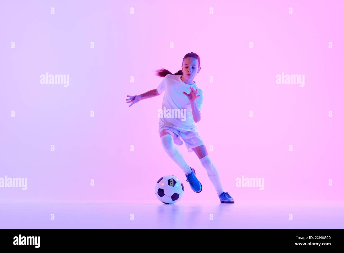 Concentrated teen girl, soccer player training, dribbling ball against ...