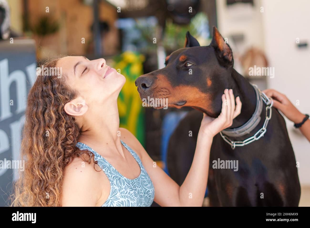 Two teenage girls playing with their doberman breed dog in the backyard ...