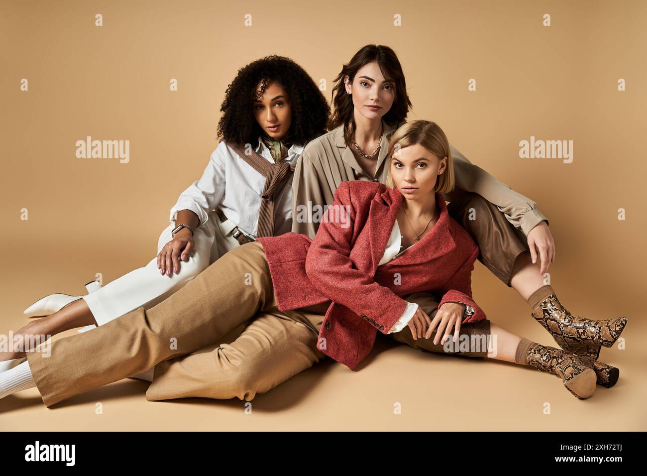 Three young, stylish, multicultural women sitting on the ground, posing ...