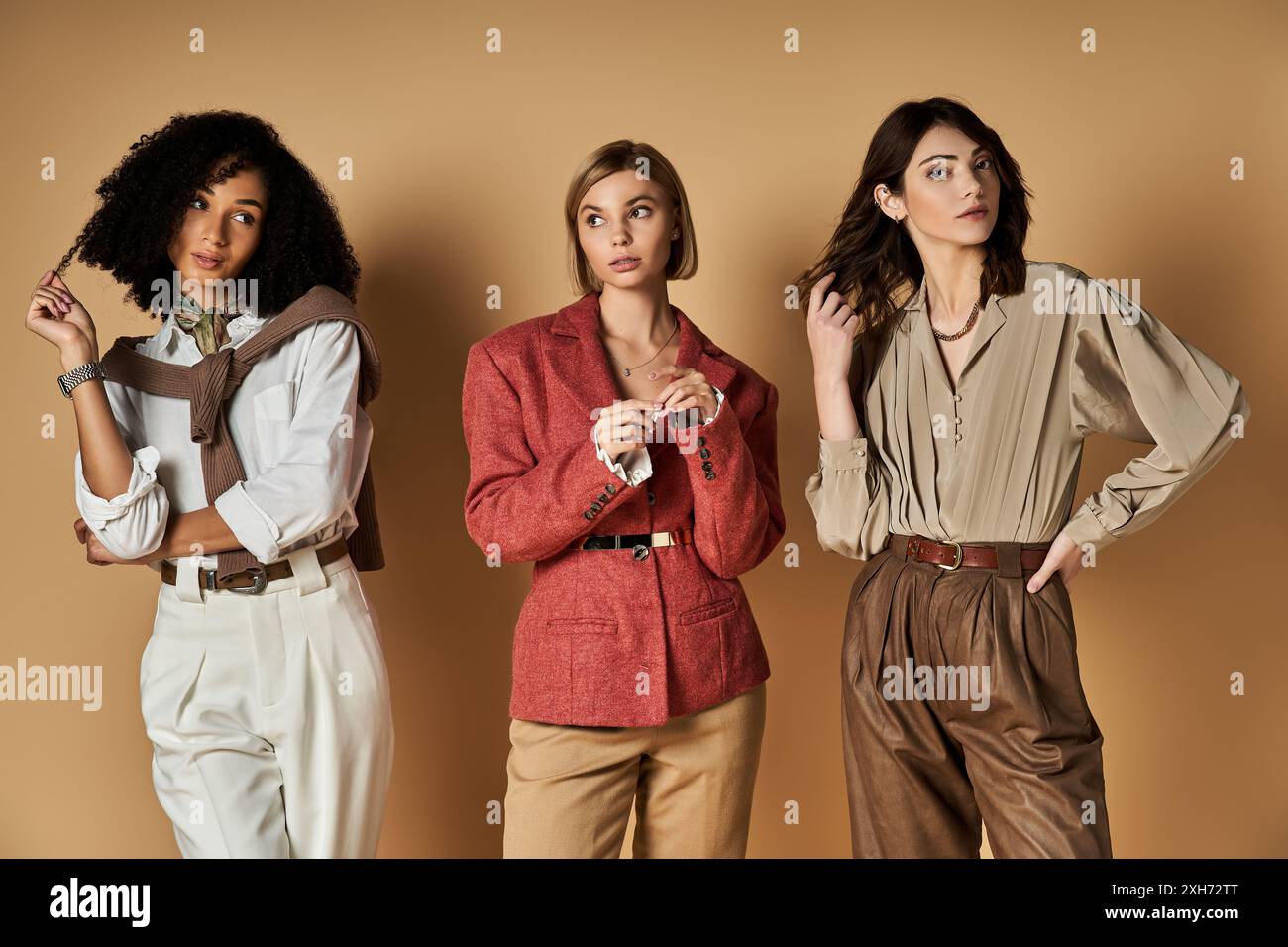 Three young multicultural women in chic outfits stand side by side ...