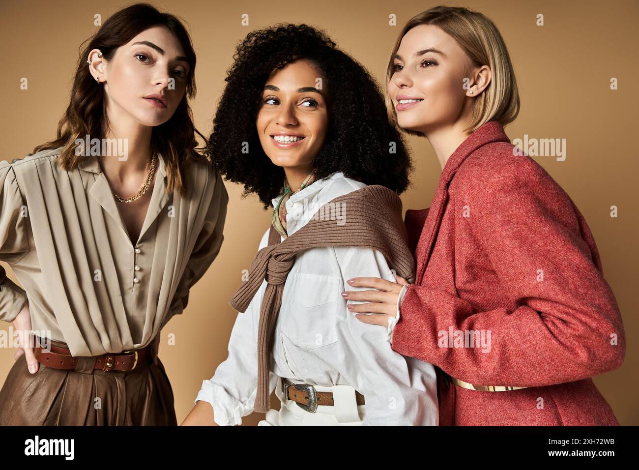 Three young beautiful multicultural women standing together in stylish ...