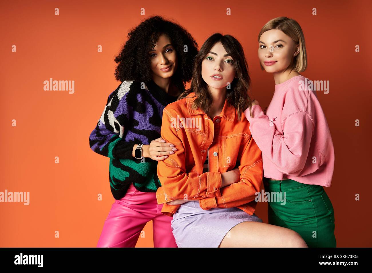 Three young, beautiful multicultural women in stylish attire posing for ...