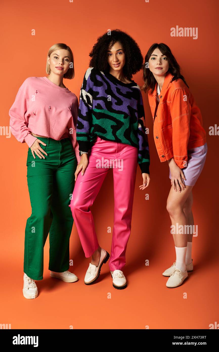 Three young, beautiful women in colorful outfits stand together ...