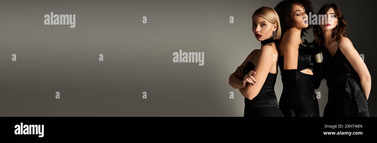Three beautiful young women in elegant black dresses pose together on a ...