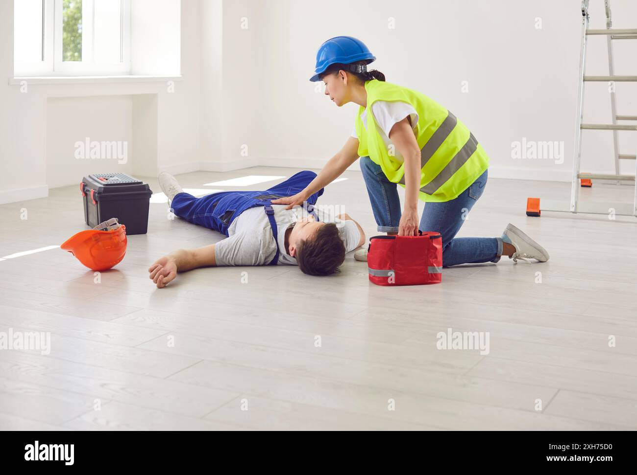 Injured unconscious young man worker lying on building site with woman ...
