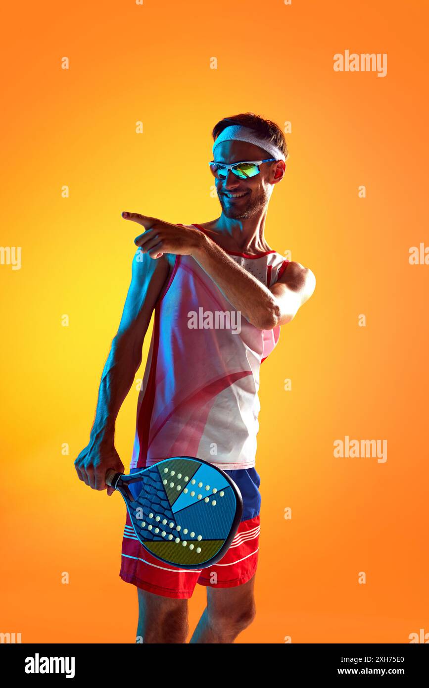 Man in sportswear and sunglasses holding padel tennis racket, pointing ...
