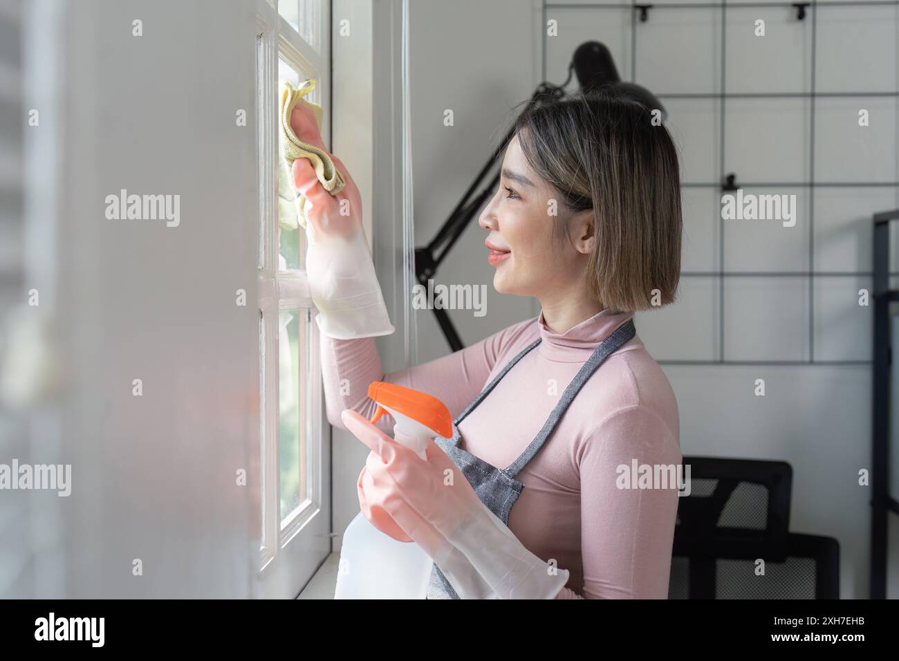 Professional Housekeeper Cleaning Window with Spray Bottle and Cloth in ...