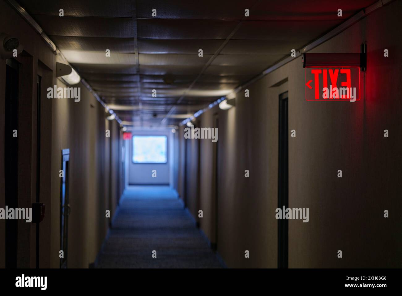 Lighted glowing red emergency exit signs in hallway with arrows ...