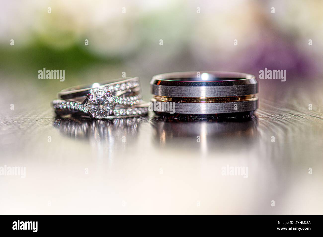 Bride and groom wedding rings on reflective surface with pink and green bokeh background Stock ...