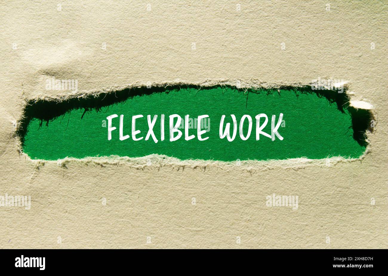 Flexible work message written on ripped torn paper with green ...