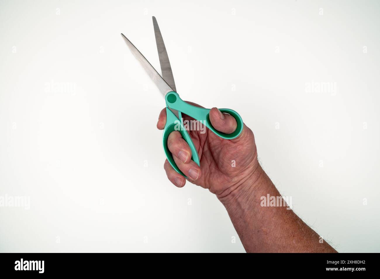 Caucasian male hand holding green handled scissors on white background ...