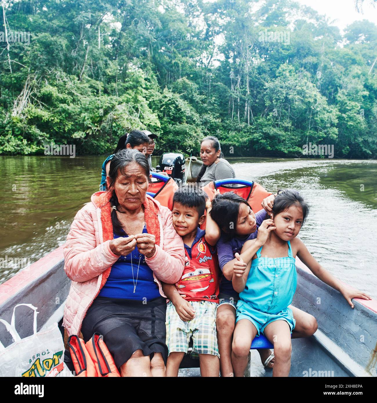 Indigenous family taking a boat down the river in the Cuyabeno wildlife ...