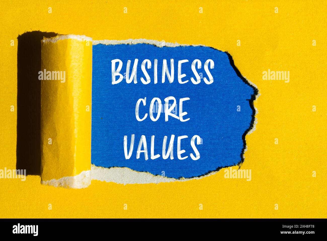 Business core values message written on ripped yellow paper with blue ...
