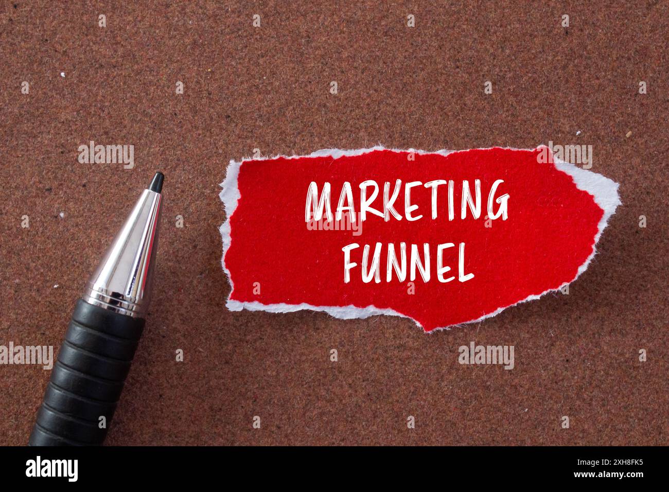 Marketing funnel message written on ripped torn red paper and a pen ...