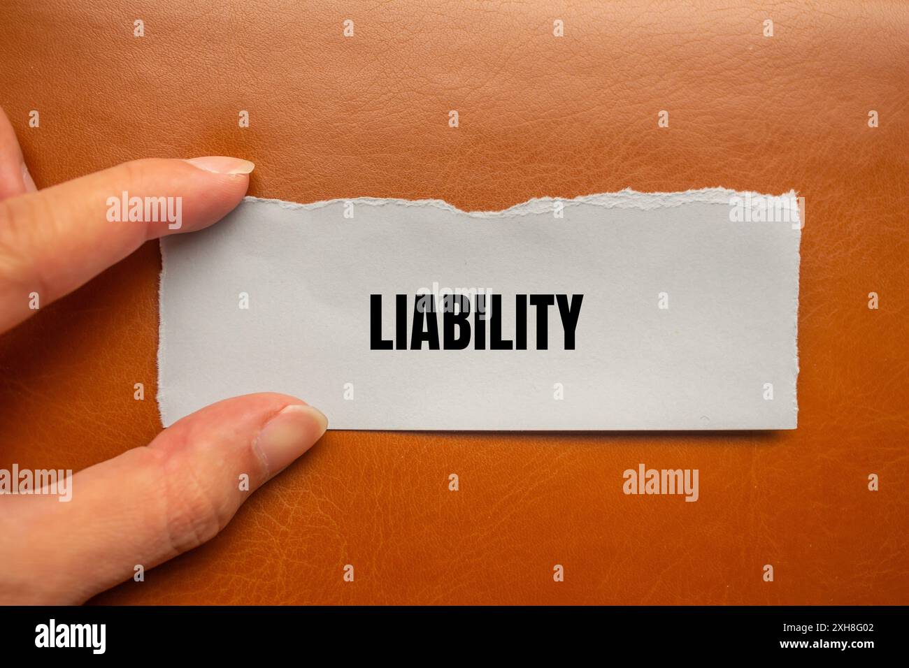Liability message written on ripped paper piece with brown background ...