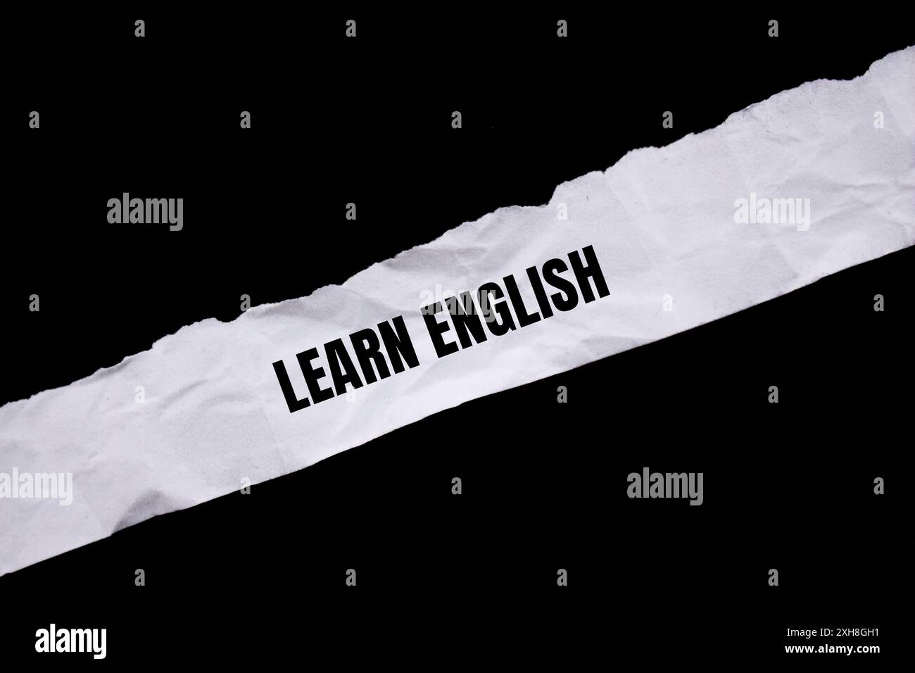 Learn english message written on ripped torn white paper with black background. Conceptual learn ...