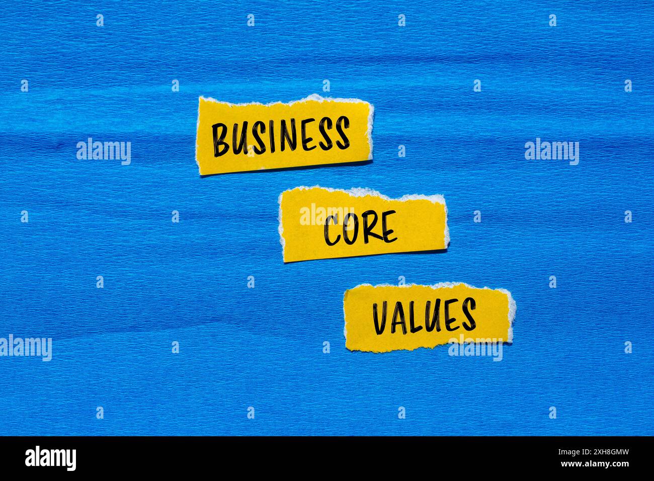 Business core values message written on ripped torn yellow paper pieces ...