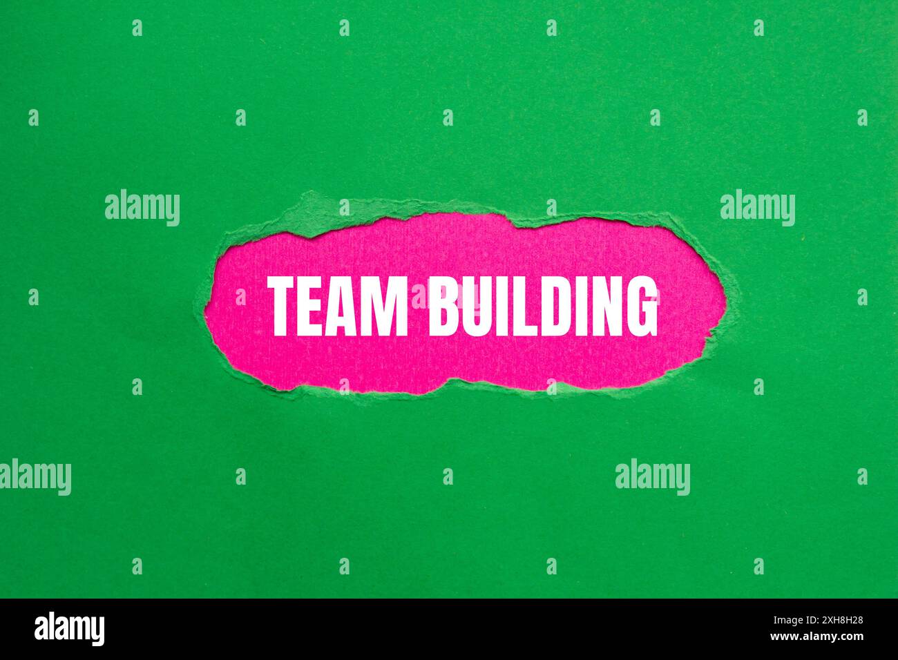 Team building message written on ripped green paper with pink ...