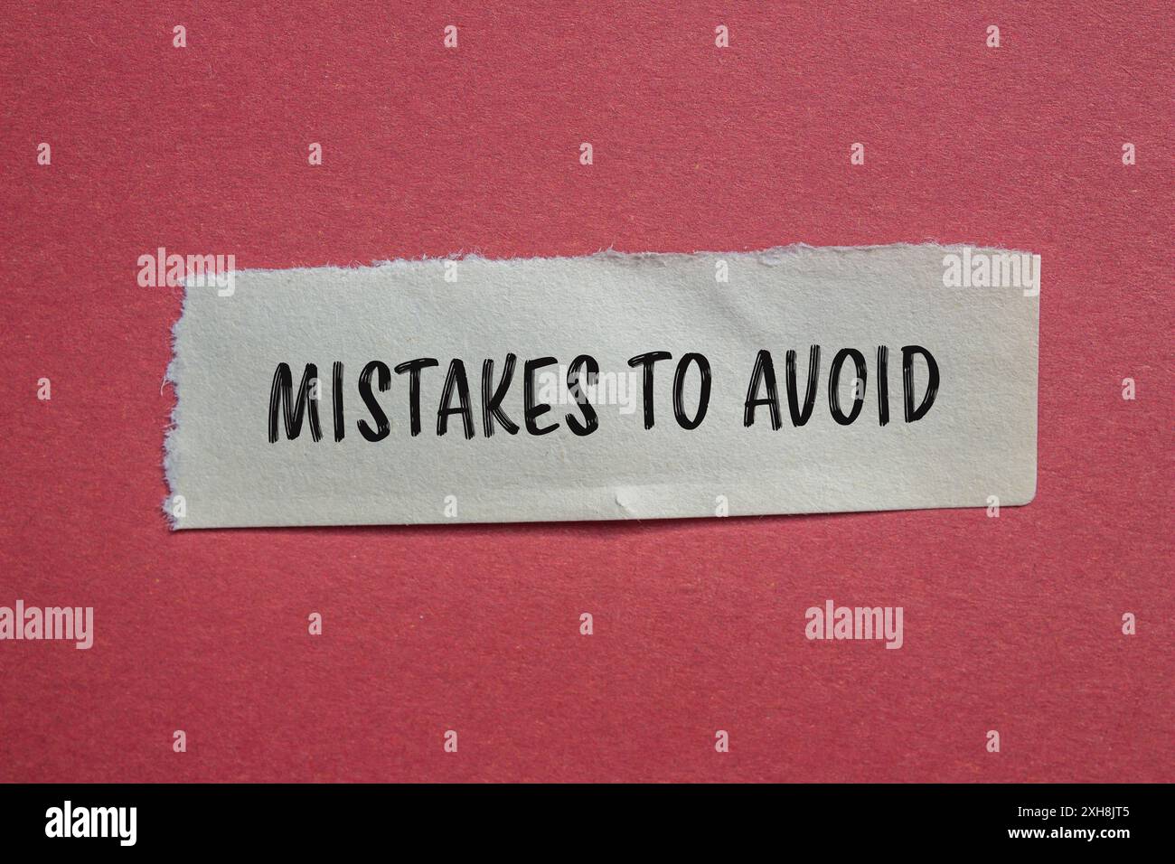 Mistakes to avoid message written on ripped paper with red background ...