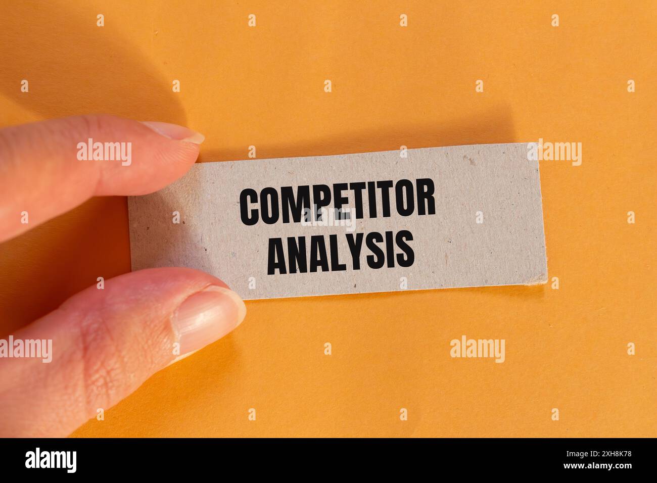 Competitor analysis message written on ripped paper piece with orange ...