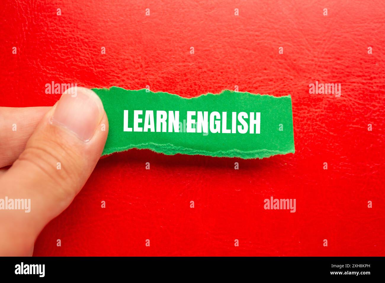 Learn english message written on ripped torn green paper with red background. Conceptual learn ...