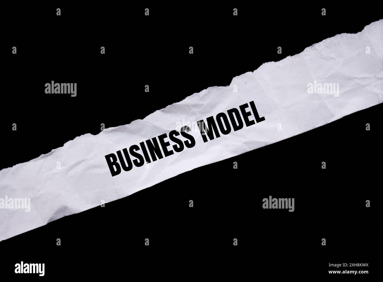 Business model message written on ripped torn white paper with black background. Conceptual ...