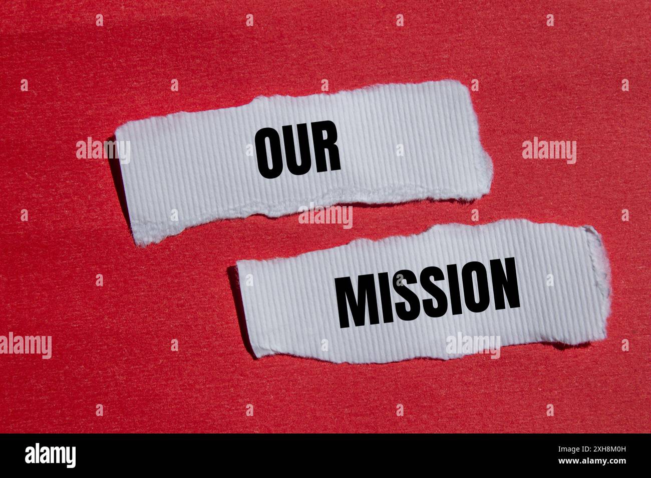 Our mission message written on ripped torn white paper with red background. Conceptual our ...