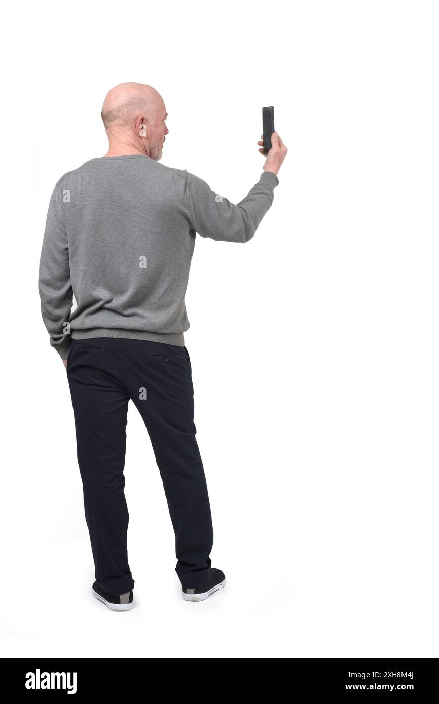 back view of a man taking a self-portrait with smartphone on white ...