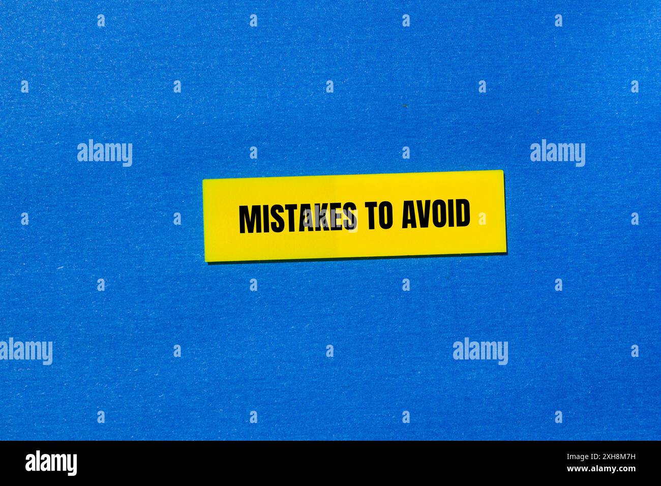 Mistakes to avoid message written on yellow paper with blue background ...