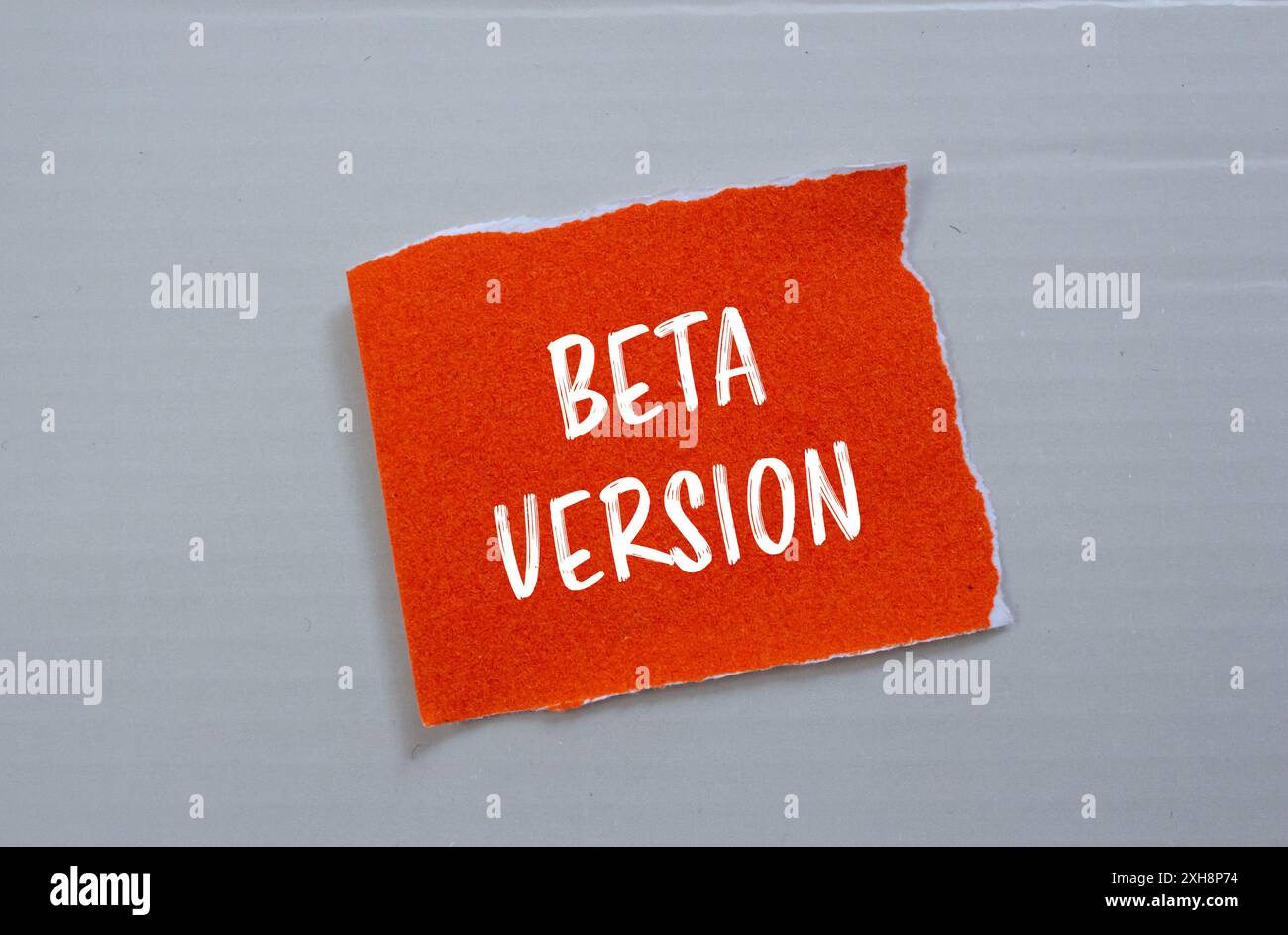 Beta version message written on ripped torn orange paper piece with gray background. Conceptual ...