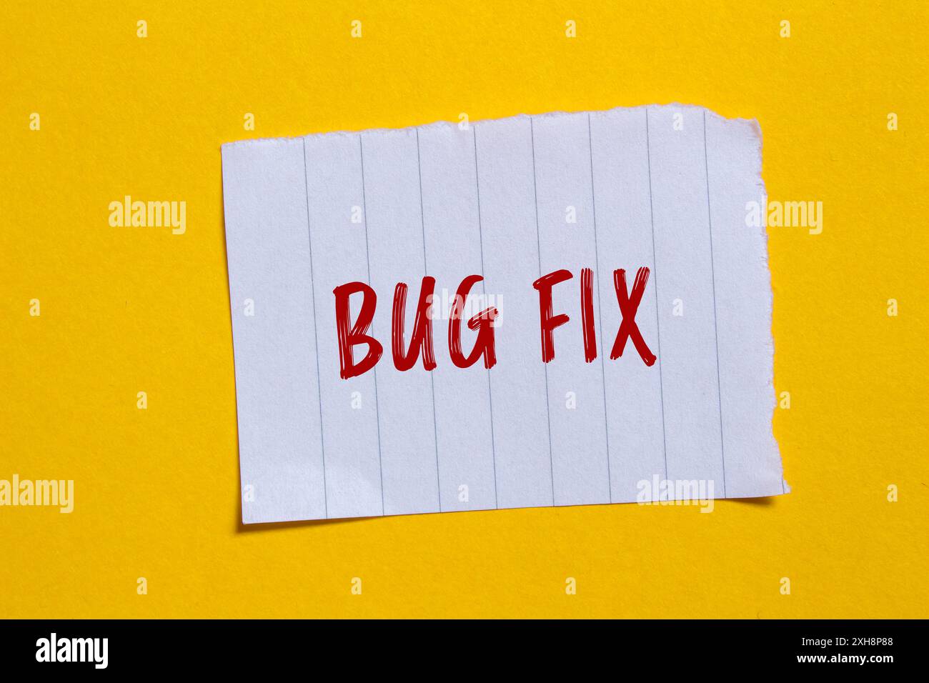 Bug fix message written on ripped torn white paper piece with yellow ...