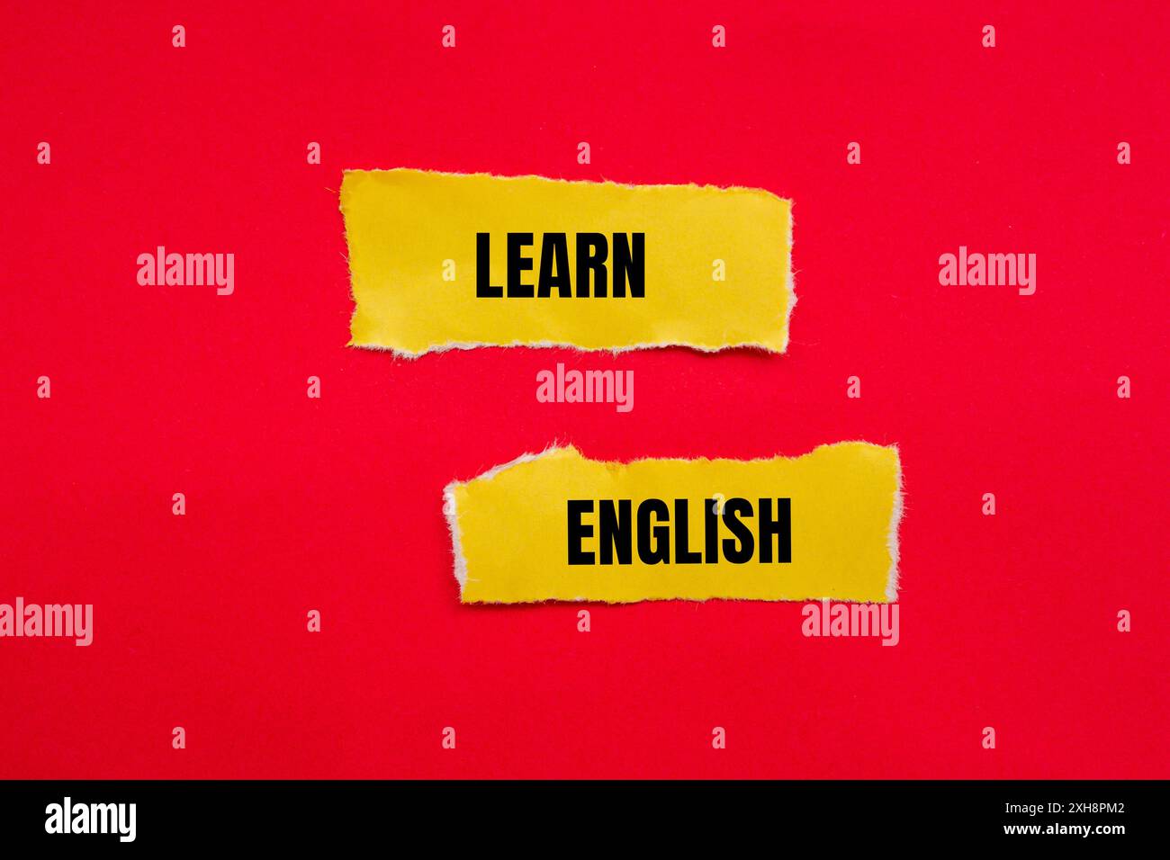 Learn english message written on ripped torn yellow paper pieces with red background. Conceptual ...