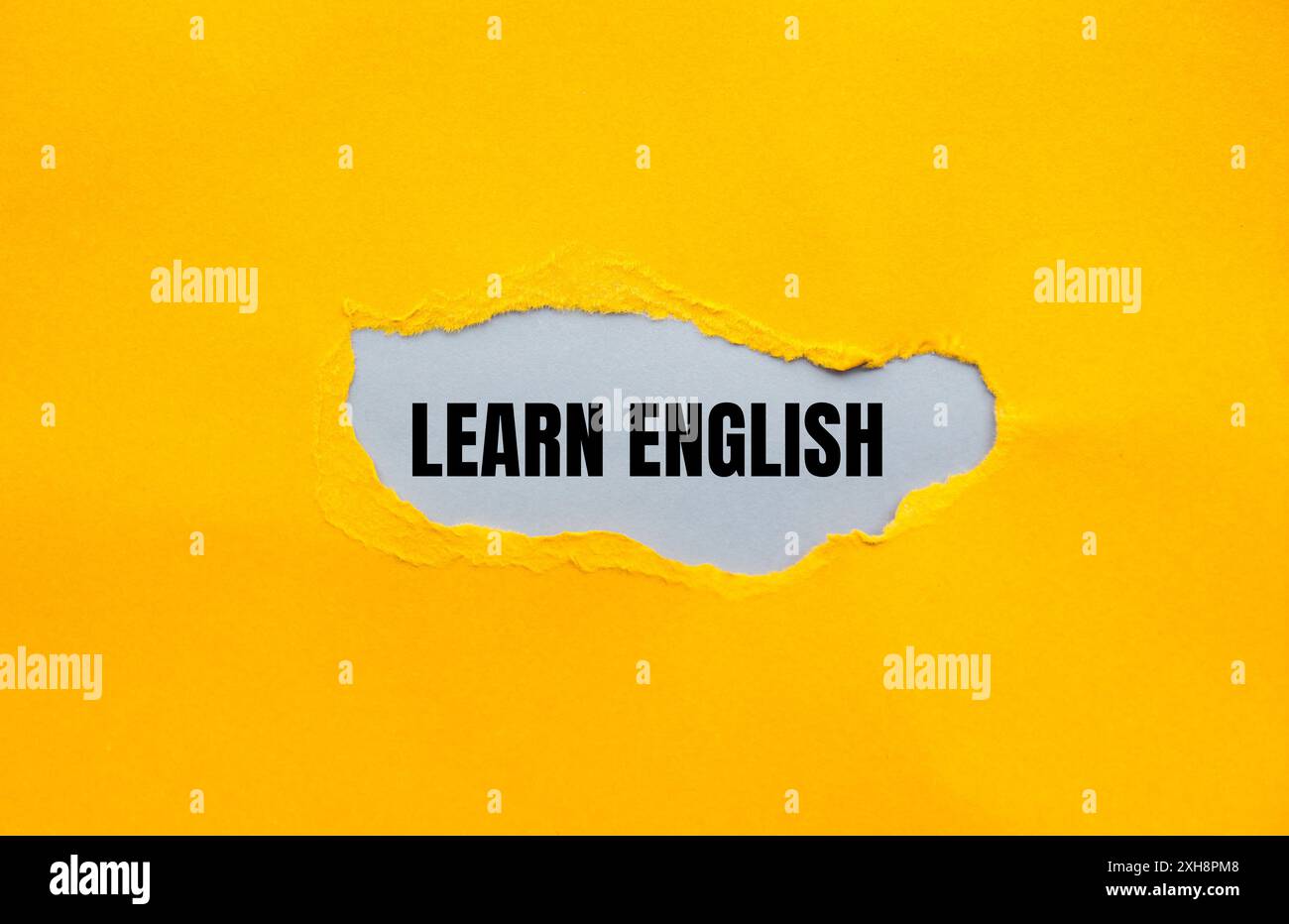 Learn english message written on ripped yellow torn paper with gray background. Conceptual learn ...