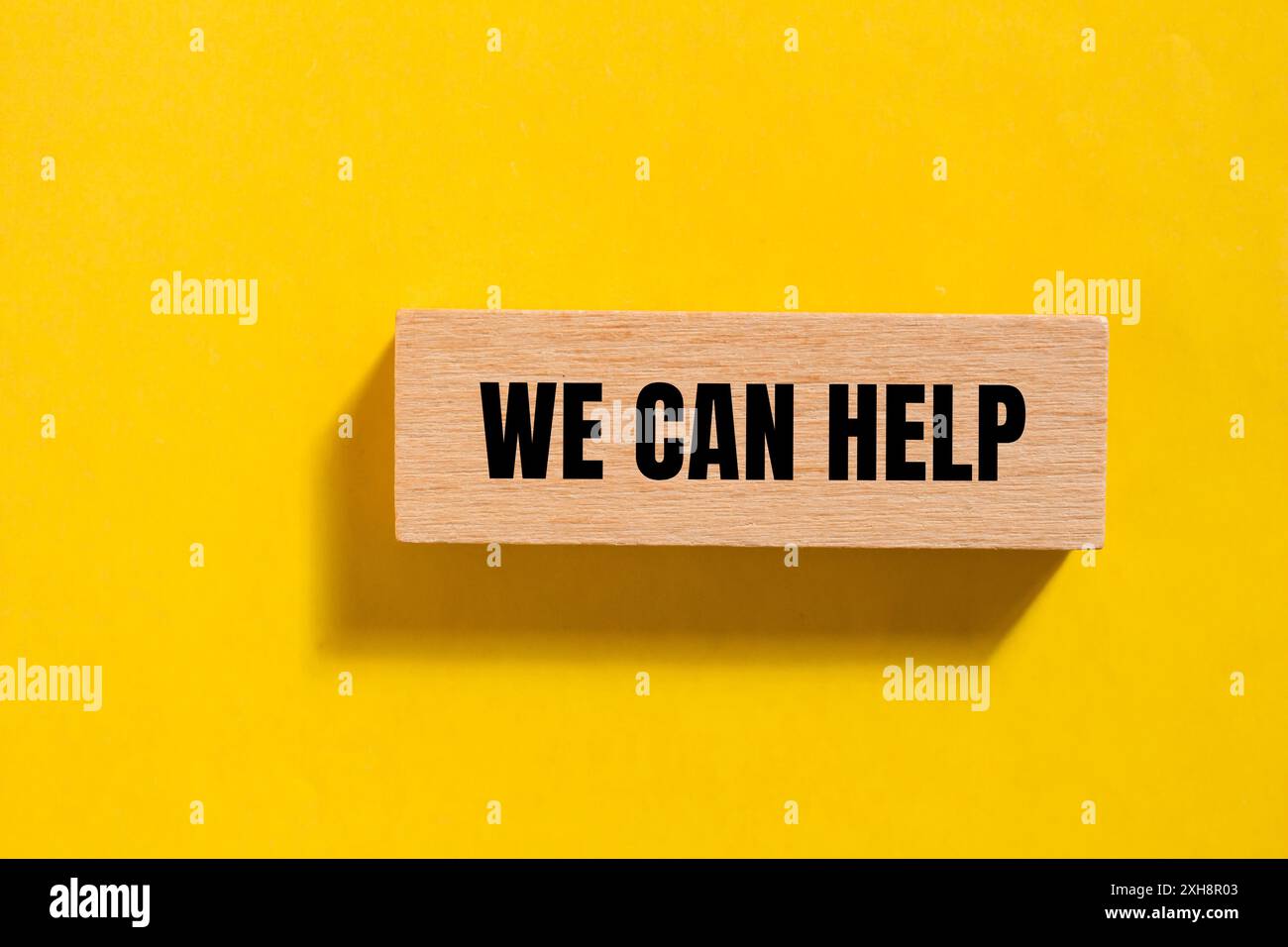 We can help message written on single wooden block with yellow ...