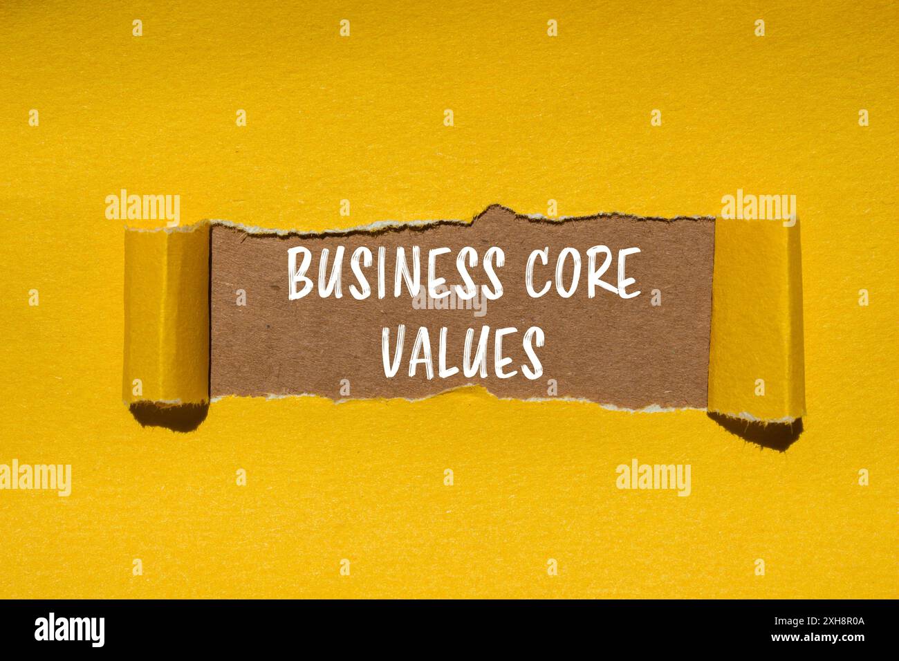 Business core values message written on ripped torn yellow paper with ...