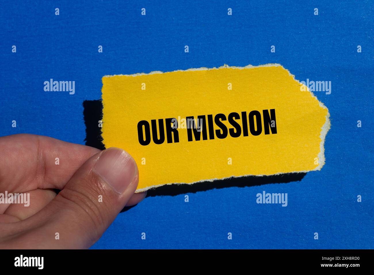 Our mission message written on ripped torn yellow paper with blue background. Conceptual our ...