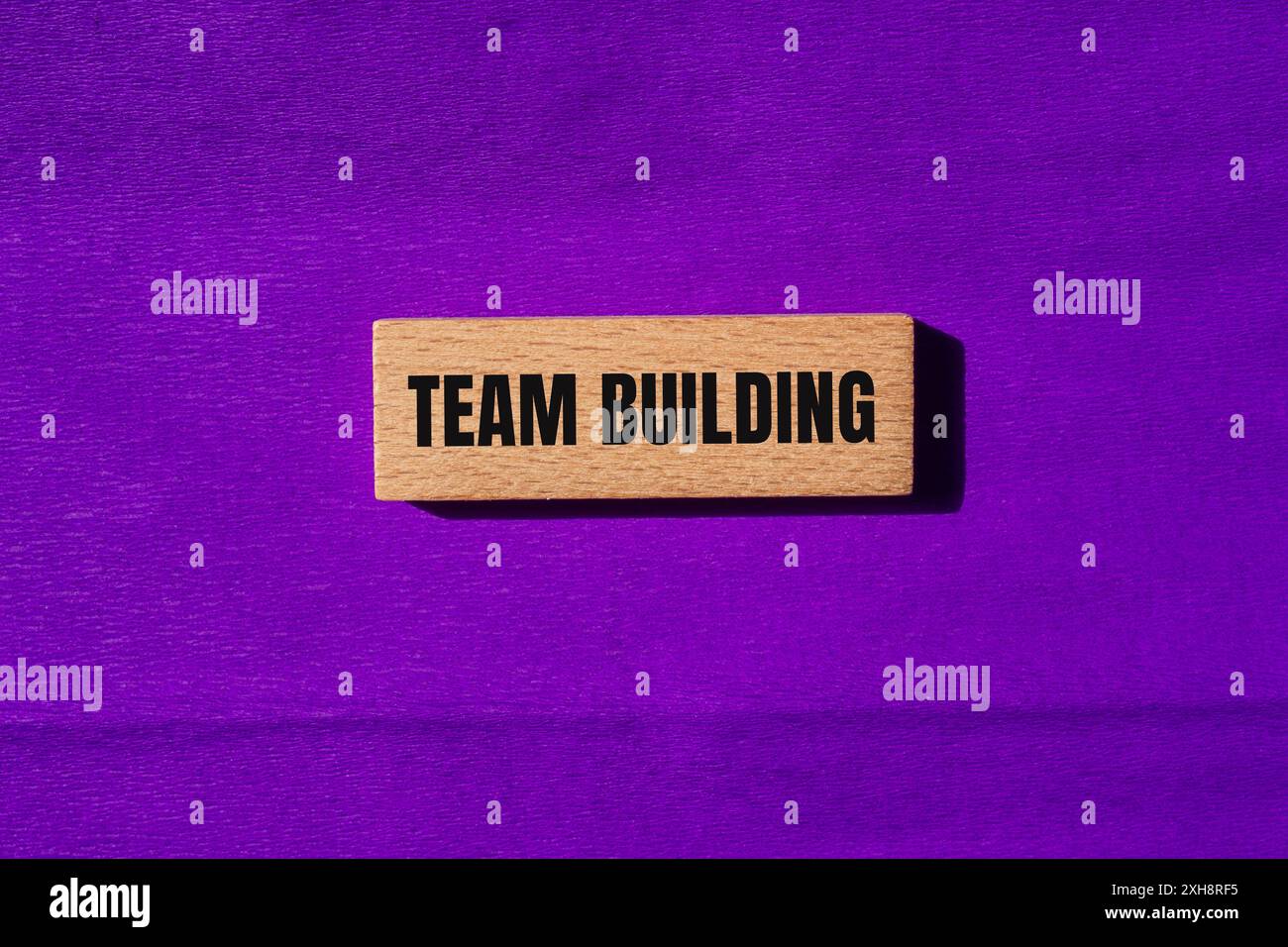 Team building message written on wooden blocks with purple background ...