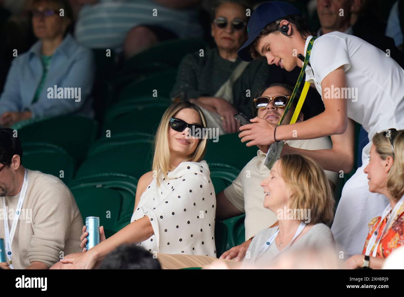 Margot Robbie poses for a photo with a fan in the stands at the ...