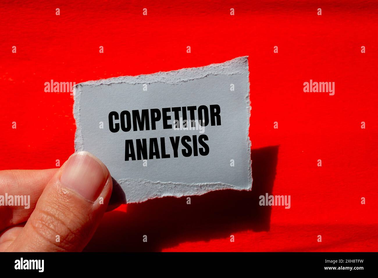 Competitor analysis message written on ripped paper piece with red ...