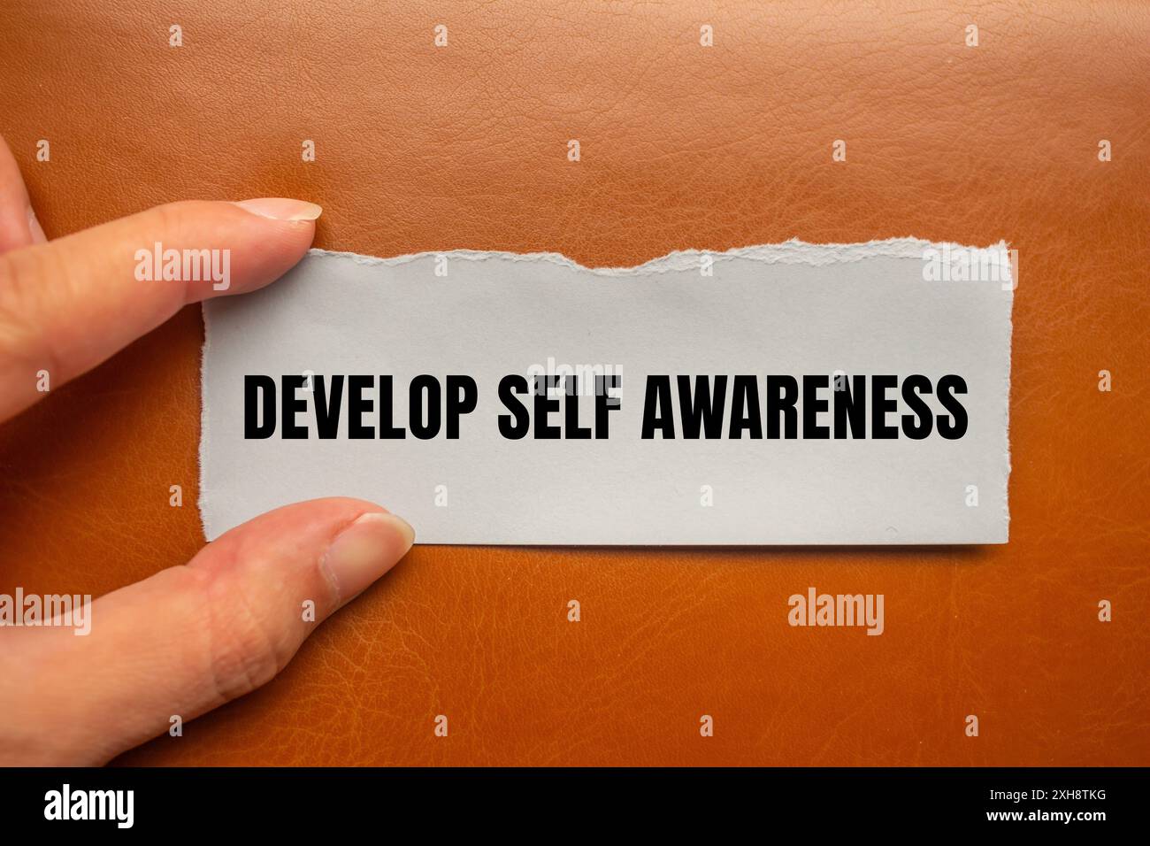 Develop self awareness message written on ripped paper piece with brown ...