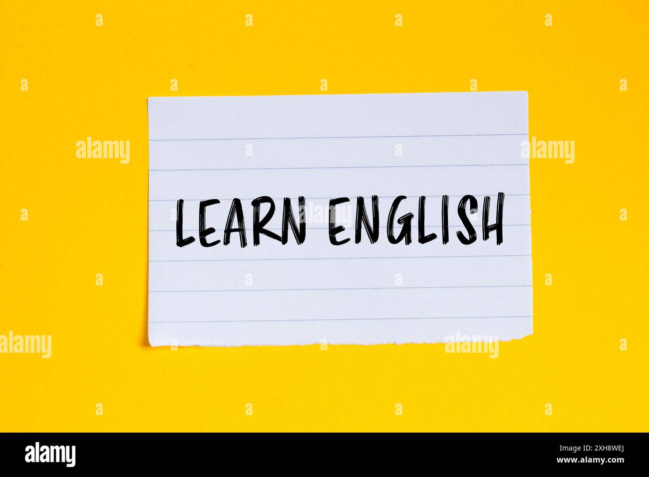Learn english message written on ripped white paper piece with yellow background. Conceptual ...