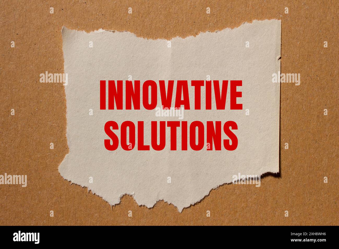 Innovative solutions message written on ripped paper with cardboard background. Conceptual ...