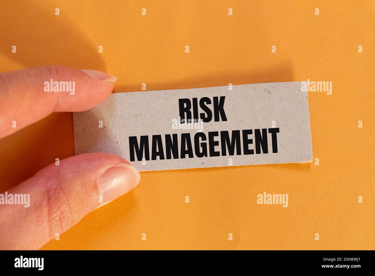Risk management message written on ripped paper piece with orange ...