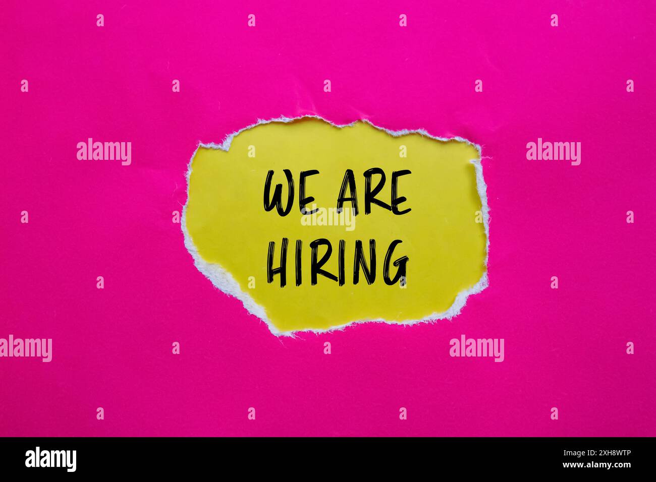 We are hiring words written on ripped pink paper with yellow background. Conceptual we are ...