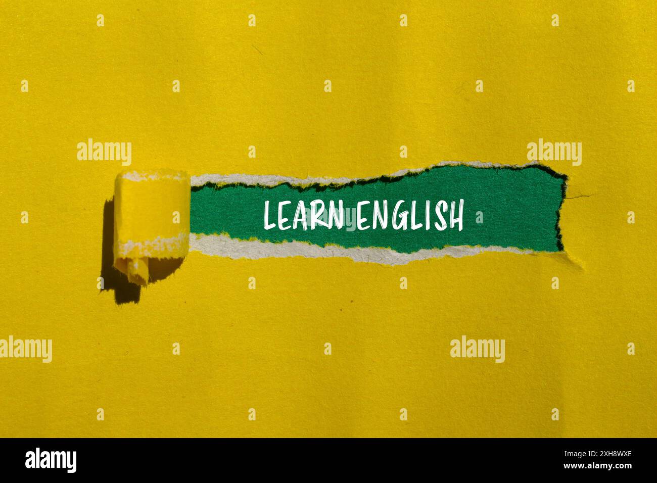 Learn english message written on ripped yellow paper with green background. Conceptual learn ...